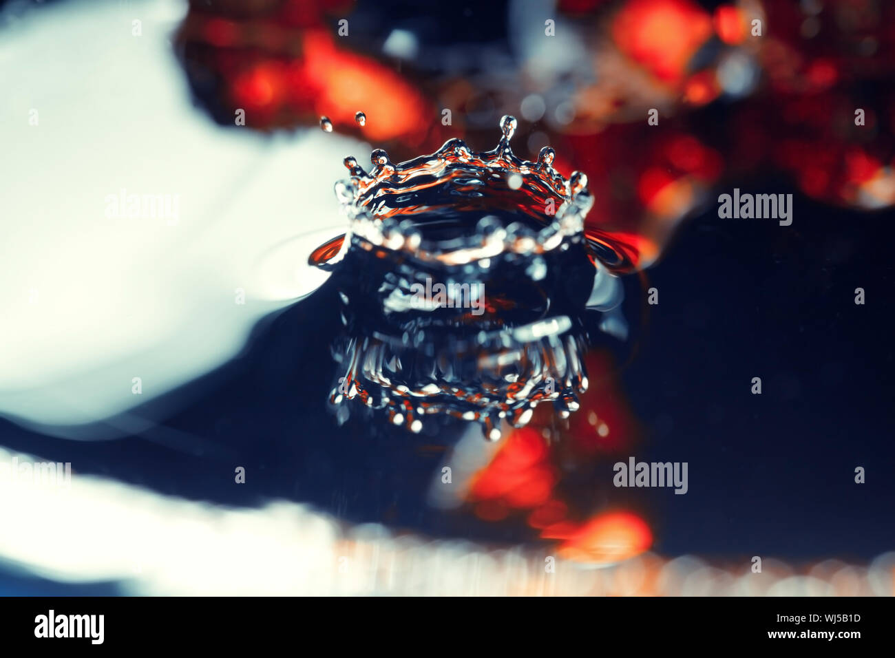 Extremely macro photo of the liquid drop falling on a wet colorful ...