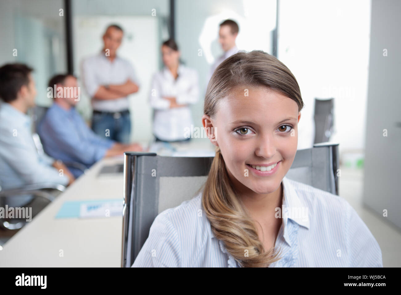Portrait of a pretty young executive with her team in the background ...