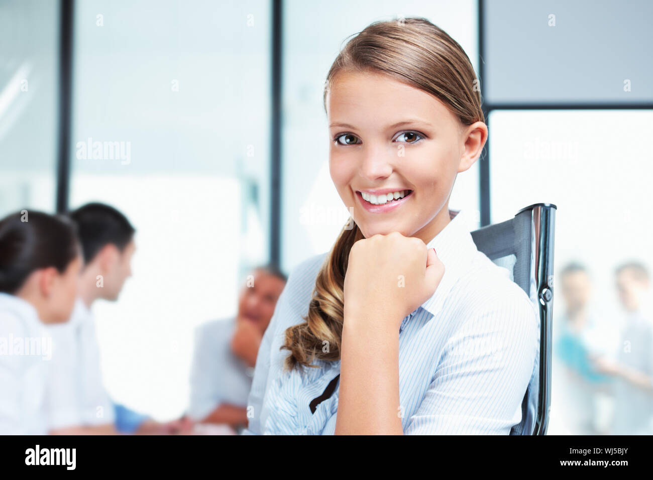 Portrait of a pretty young woman with her team in the background Stock ...