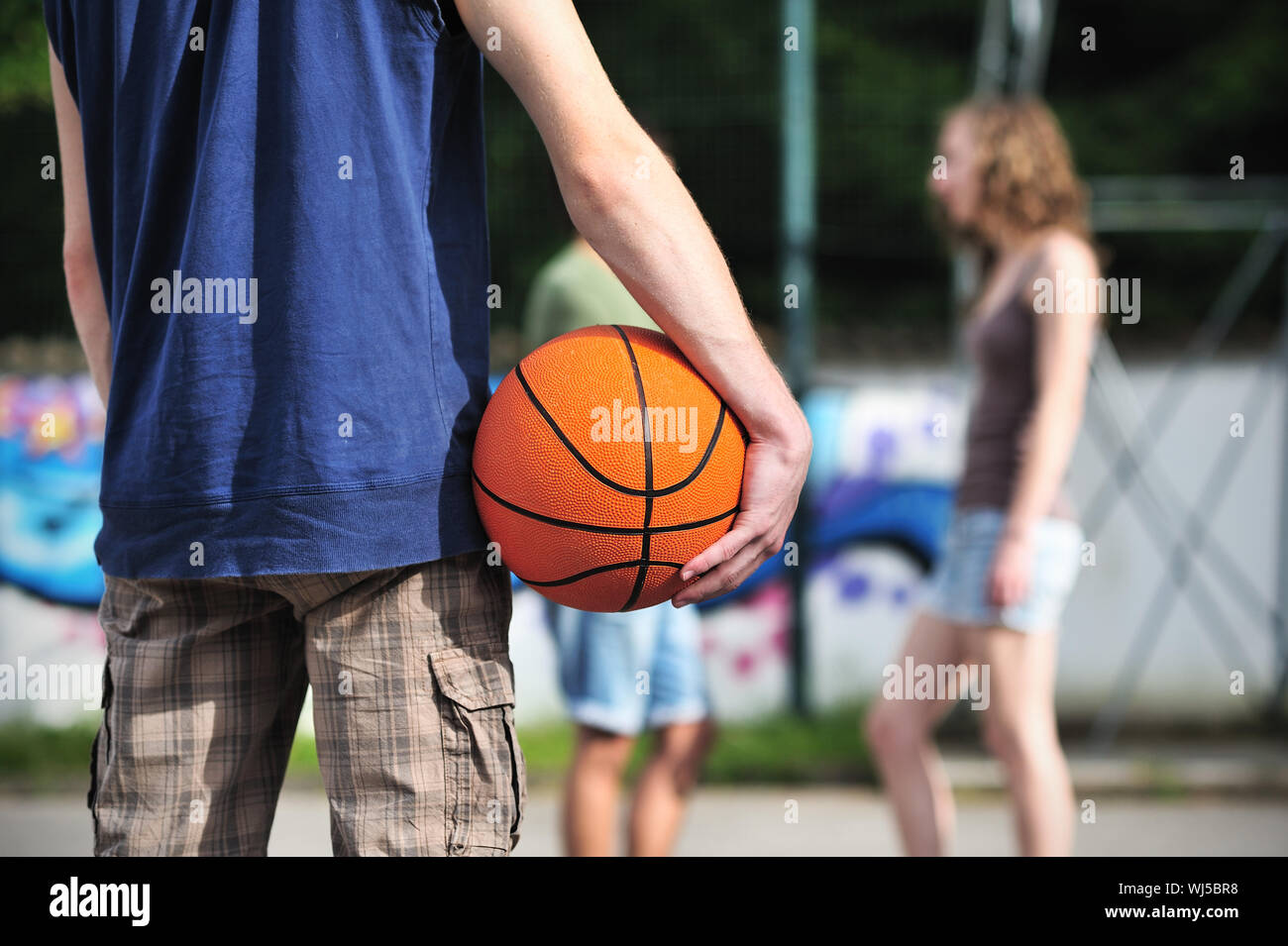 Group of friends talking and taking a break after playing basketball ...