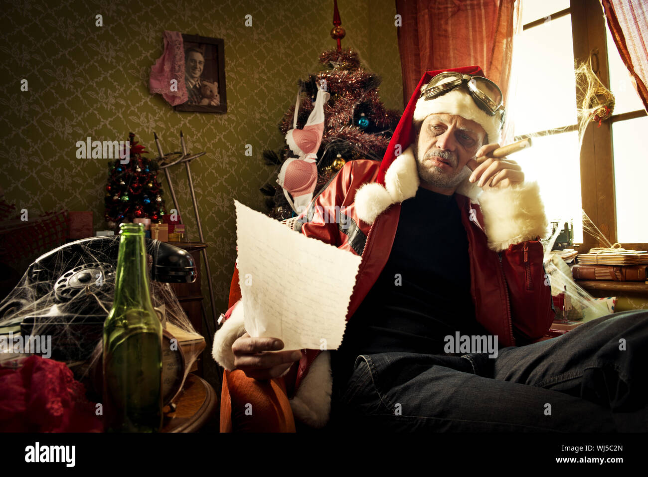 Bad Santa reading a letter at home Stock Photo - Alamy