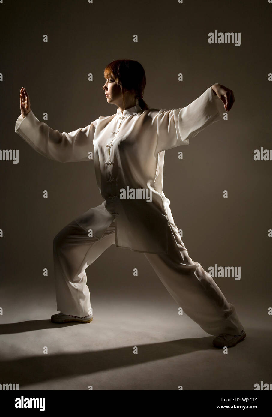 young woman in white suit make's taiji chuan exercise in studio Stock ...
