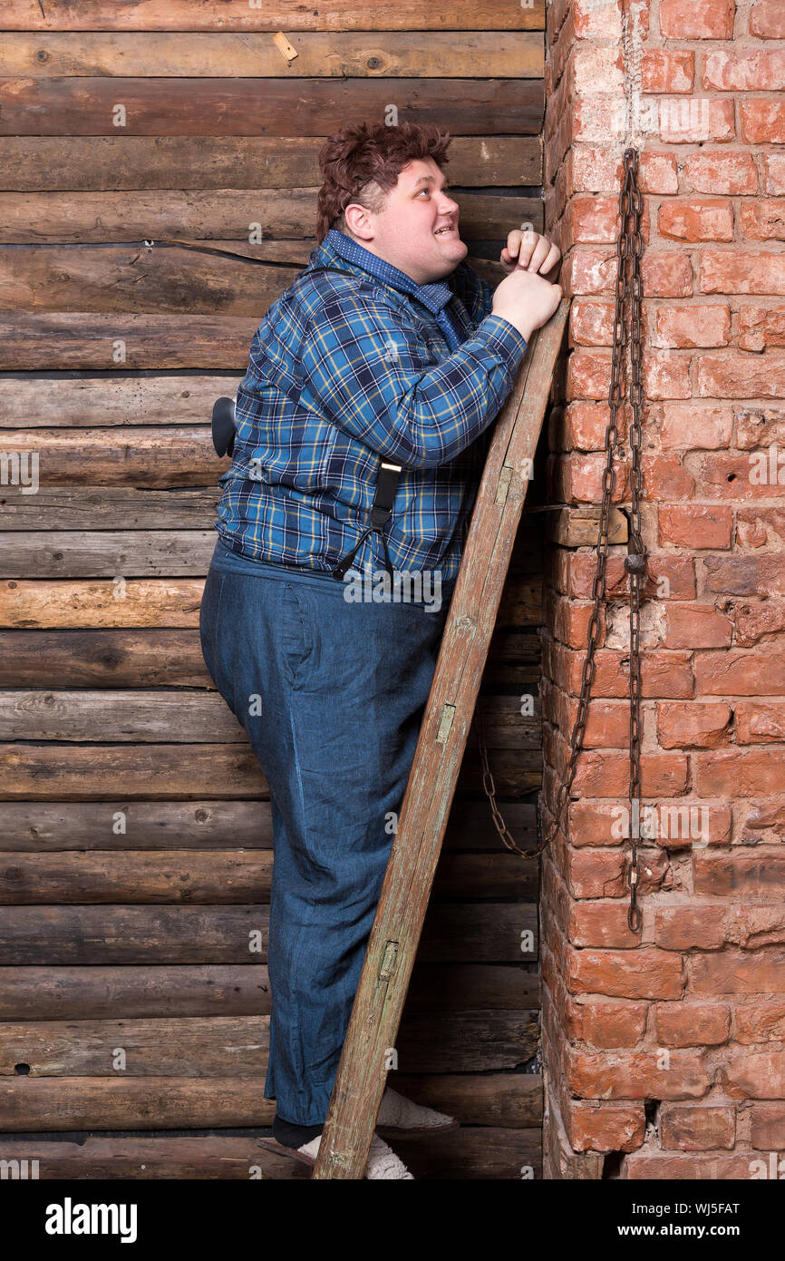 Happy overweight young man standing against a brick wall at the top of ...