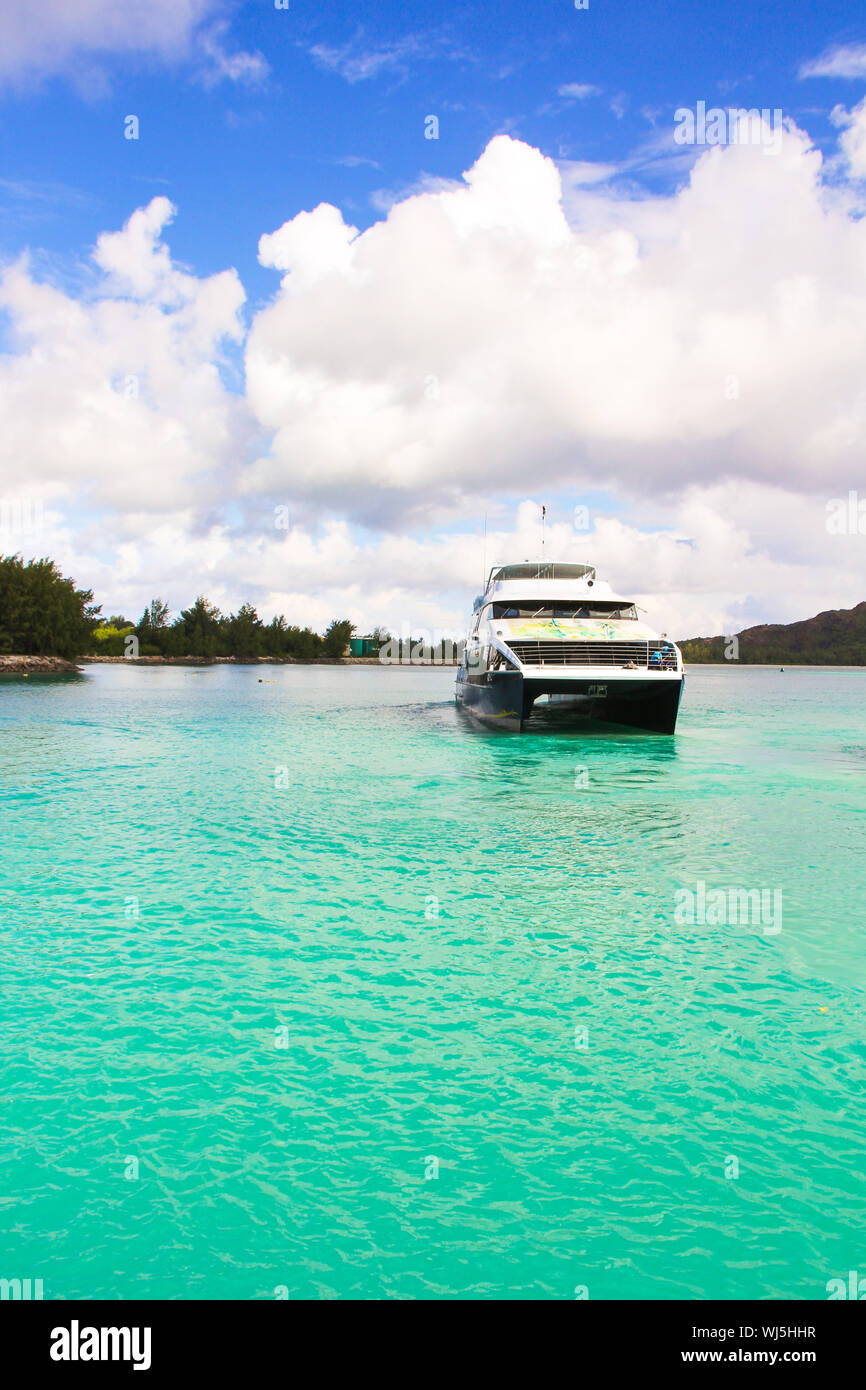 Small boat and cruiser off the coast at tropical island in turquoise ...