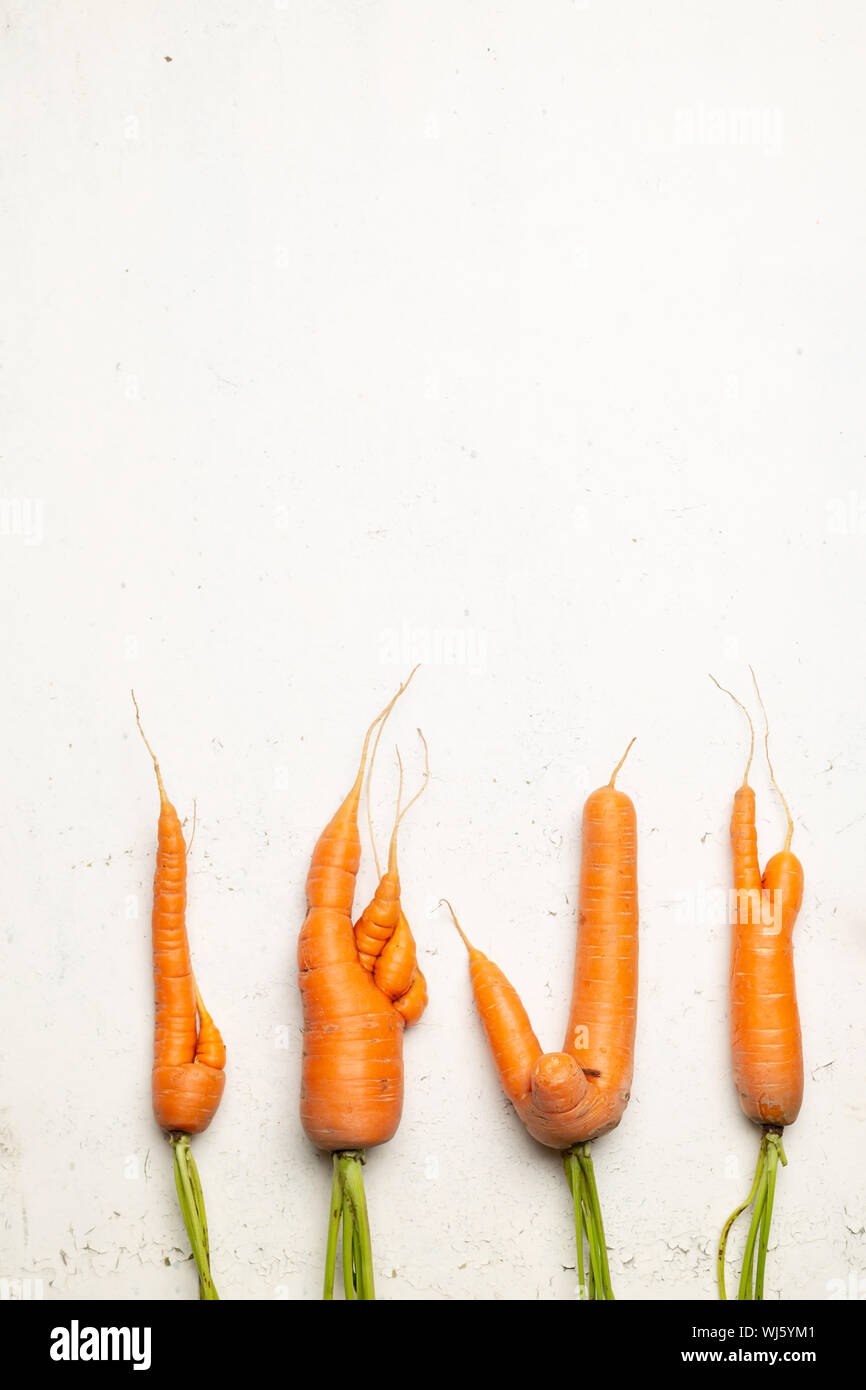 Ugly carrots on a white cracked surface. Ugly food concept, top view ...