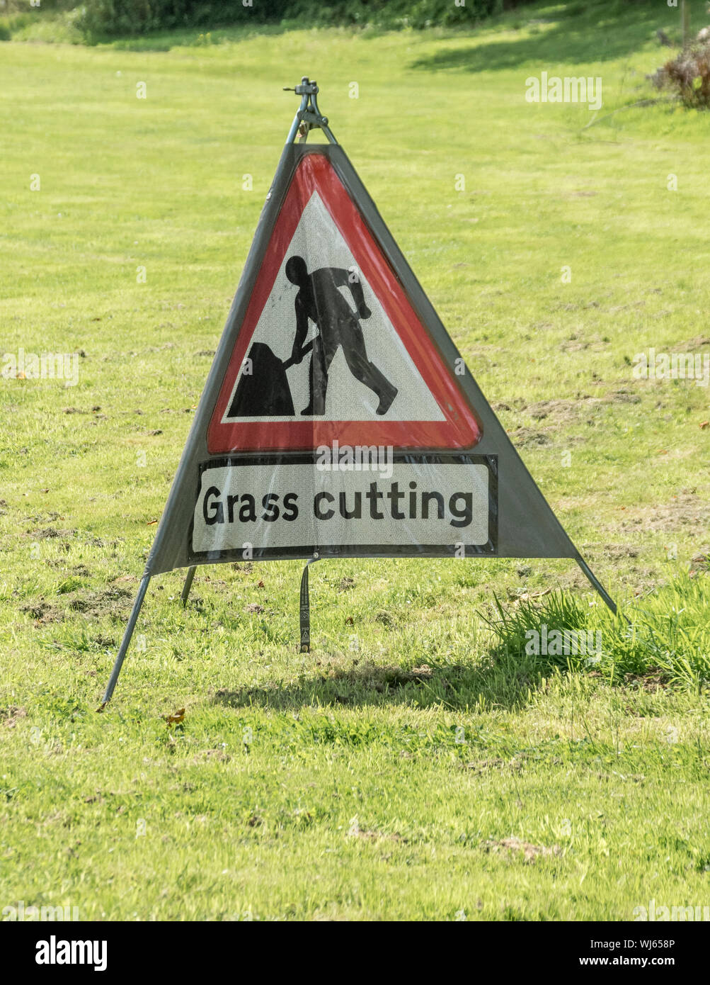 Triangular warning 'Man at Work' sign cautioning of grass cutting in ...