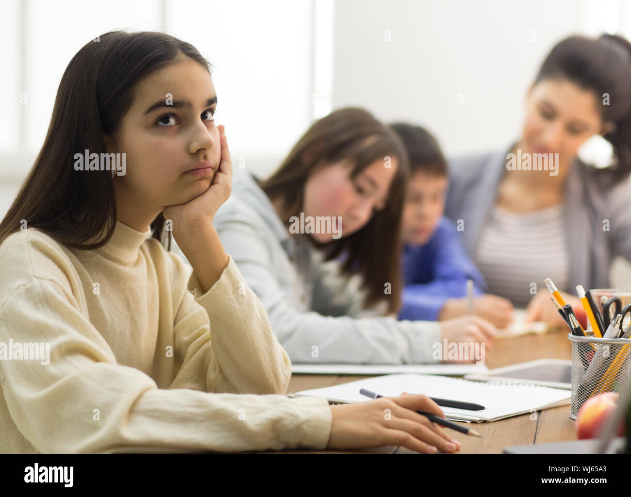 Boring lesson. Upset school girl sitting at lesson Stock Photo - Alamy