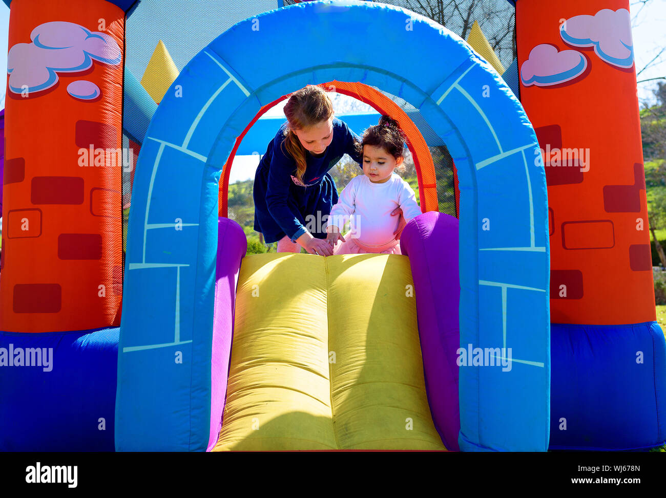 Inflatable castle outdoor at sunny summer day.Two little girls having ...