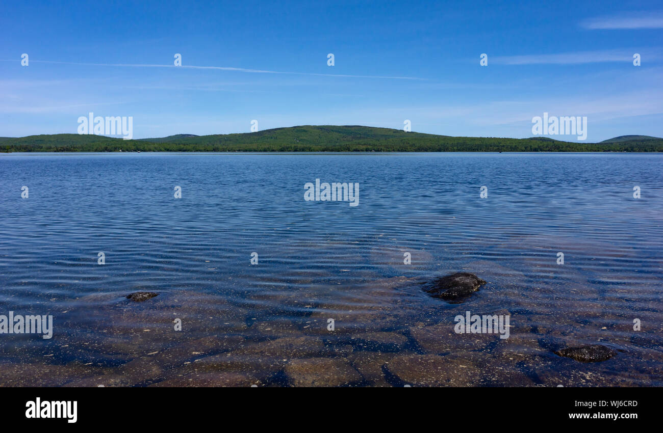 Wide view of the shoreline of Branch Lake with blue sky above and wispy ...