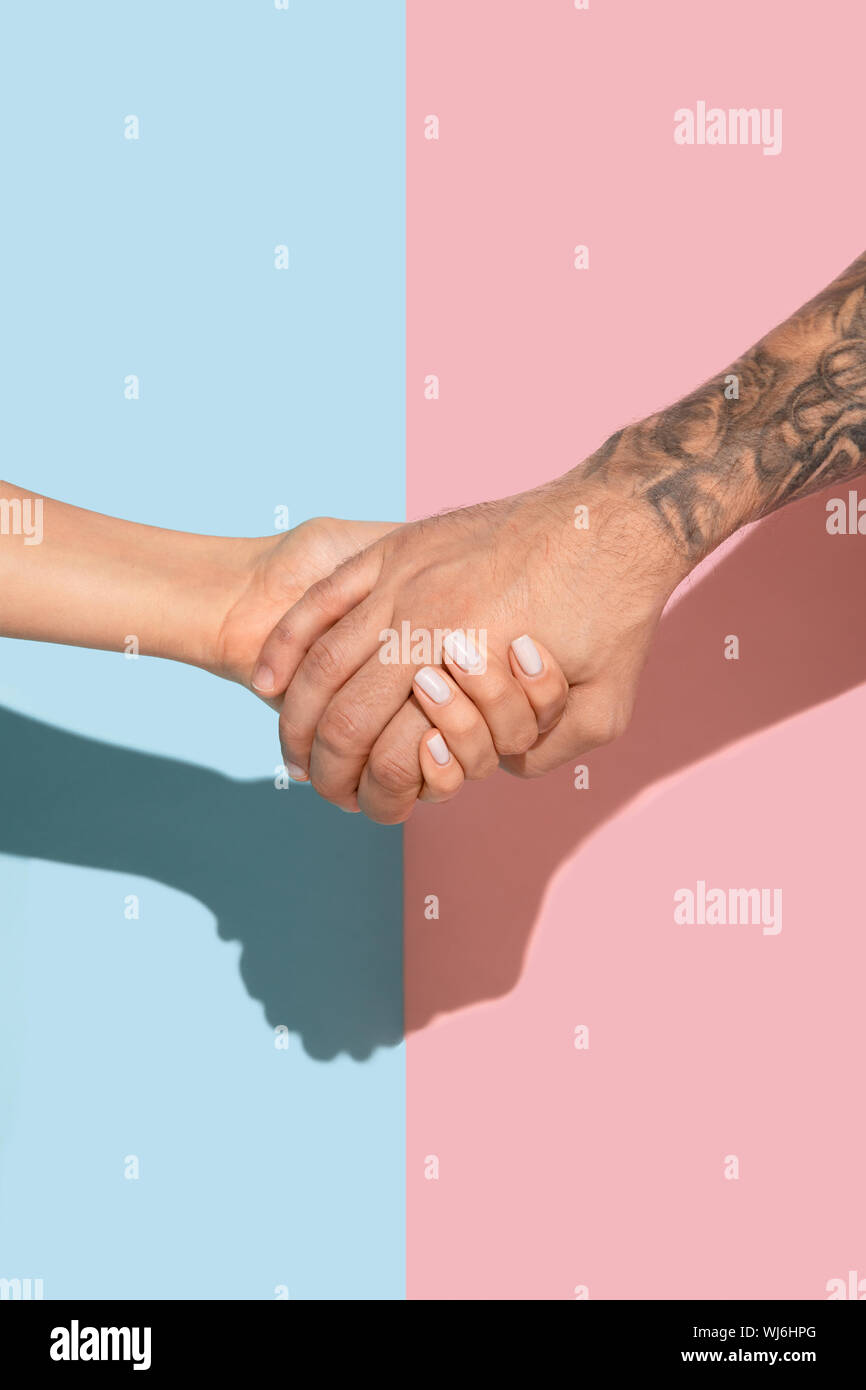 Closeup shot of human holding hands isolated on blue-pink studio ...