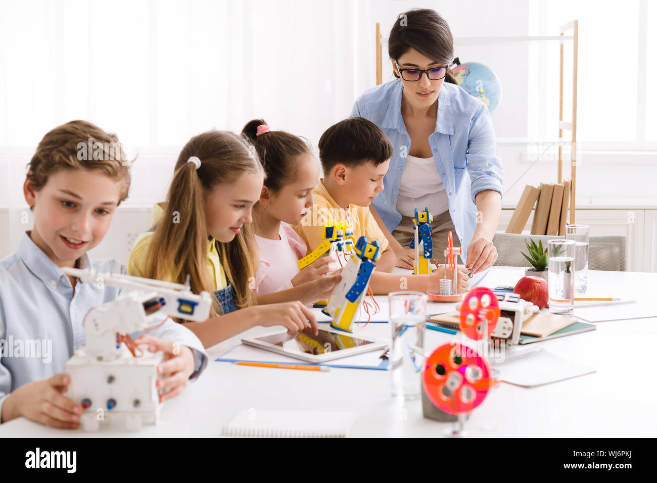 Teacher helping children with diy robots in class Stock Photo - Alamy