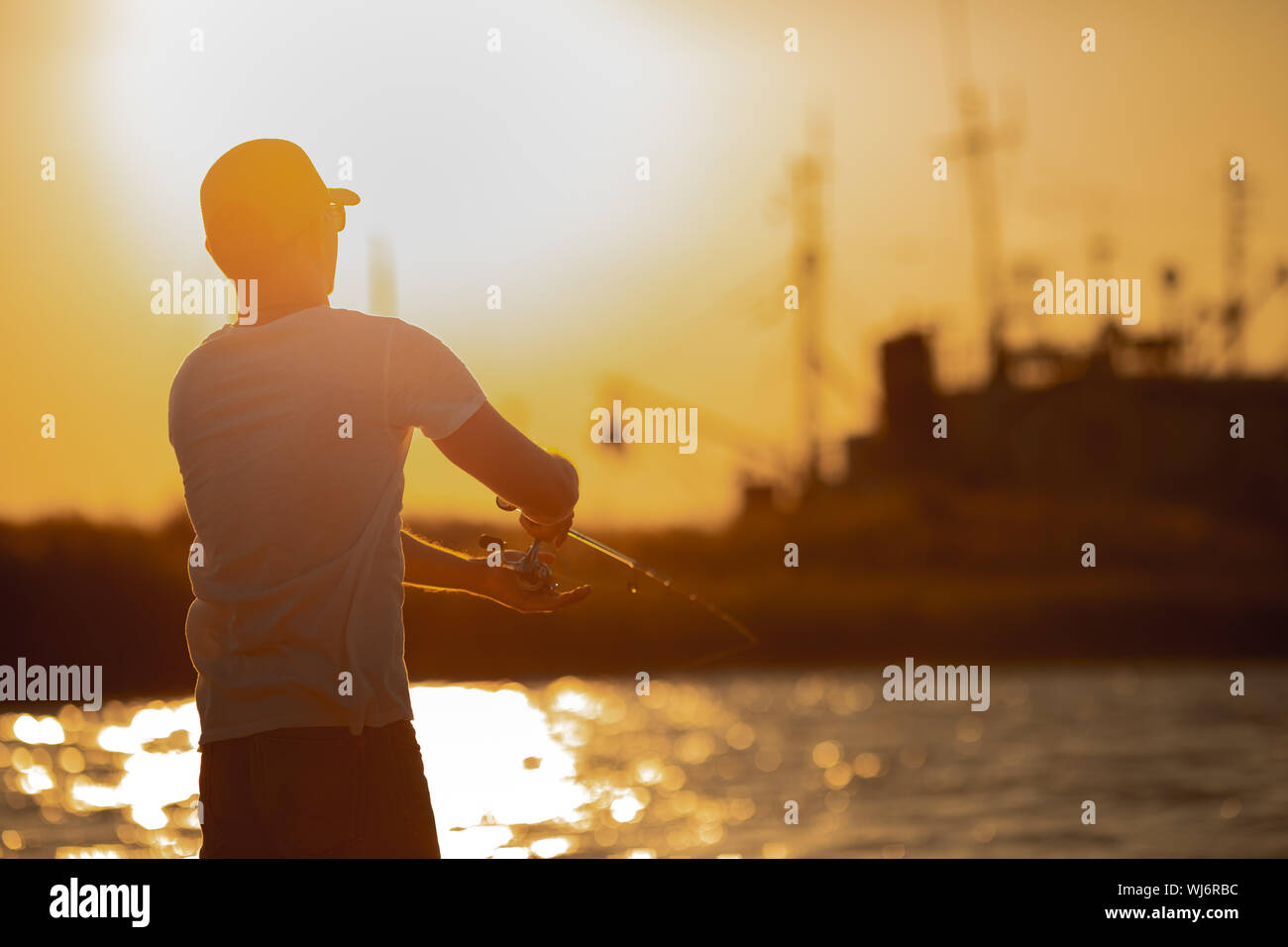 Young man fishing at sea from the shore at sunset. soft light ...