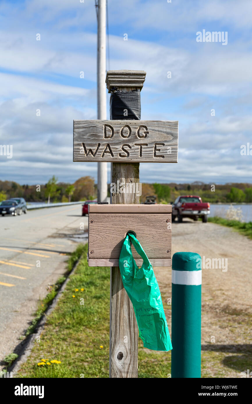 Wood dog waste sign with green bags for picking up dog poop in a public ...