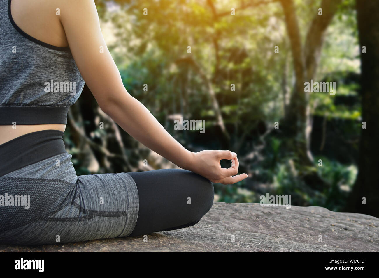 Side View Of Woman Meditating On Rock At Park Stock Photo - Alamy