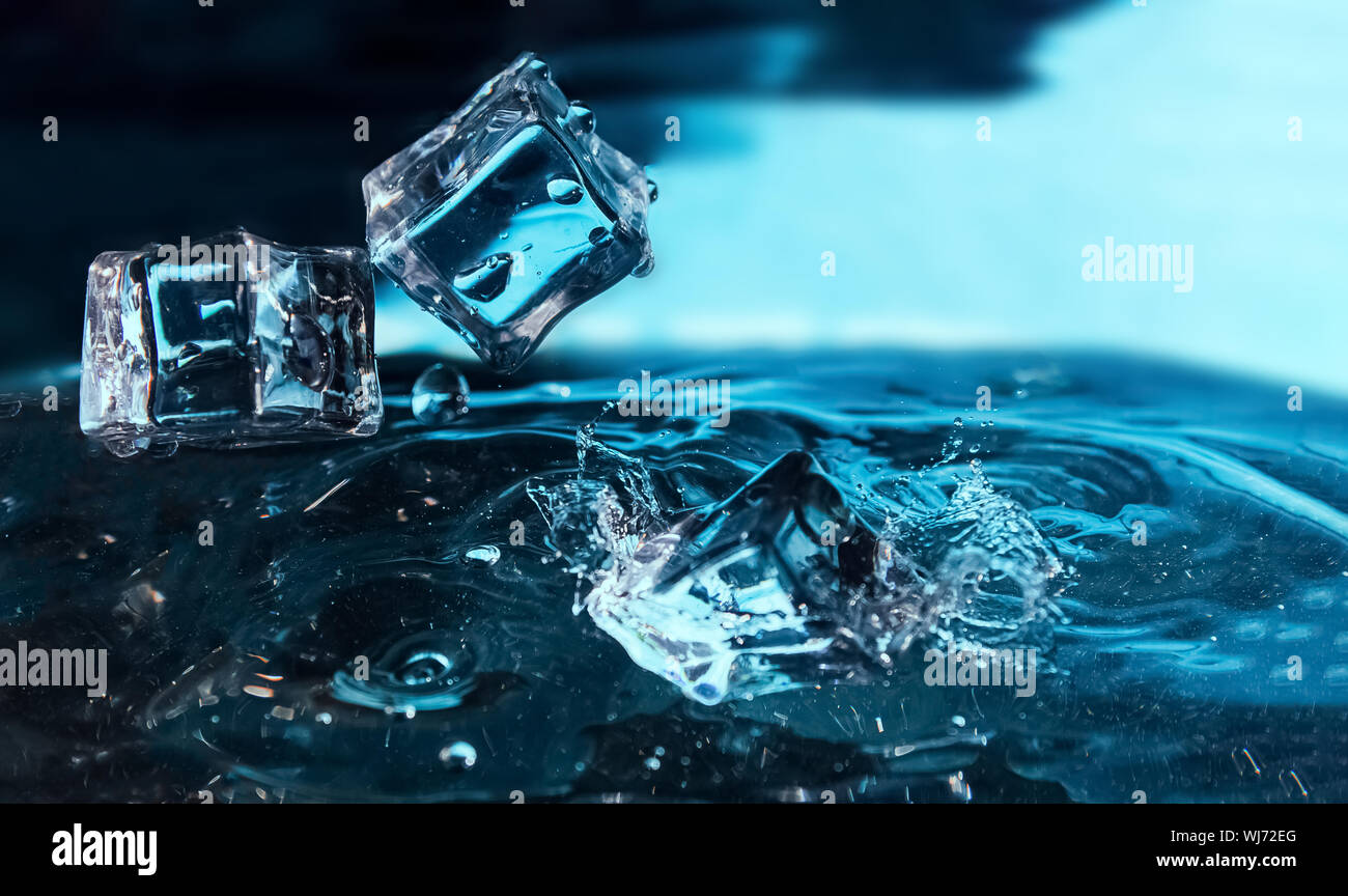 Ice cubes falling into the blue water. Splash of ice water. Water ...