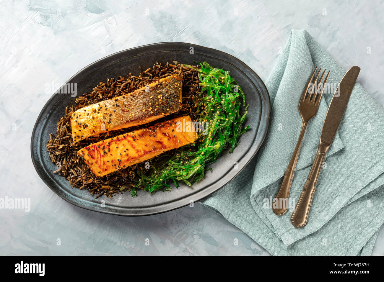 Grilled salmon with sesame seeds, wakame seaweed and wild rice, shot ...