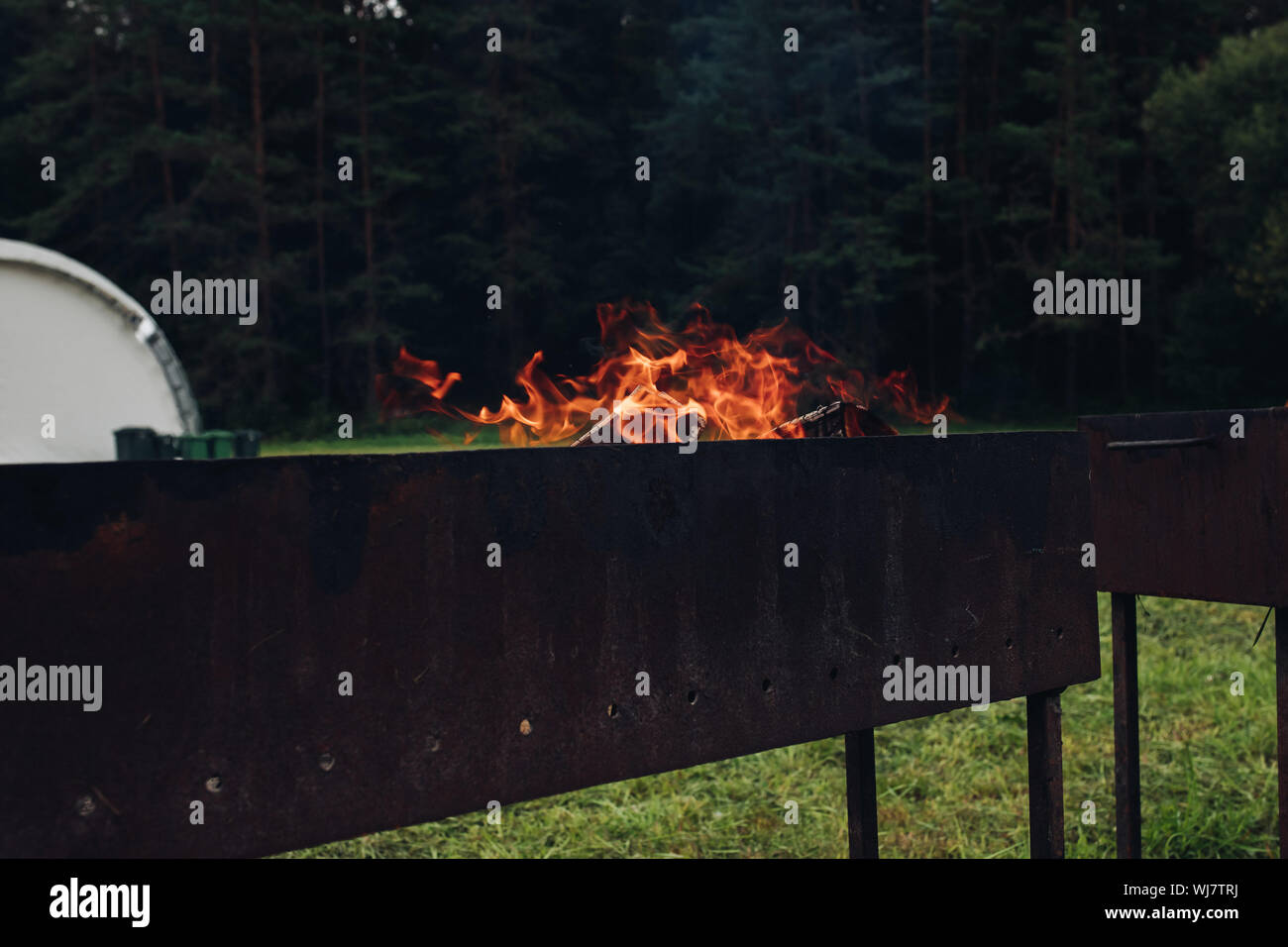 Side view of brazier with flaming fire and firewood Stock Photo - Alamy