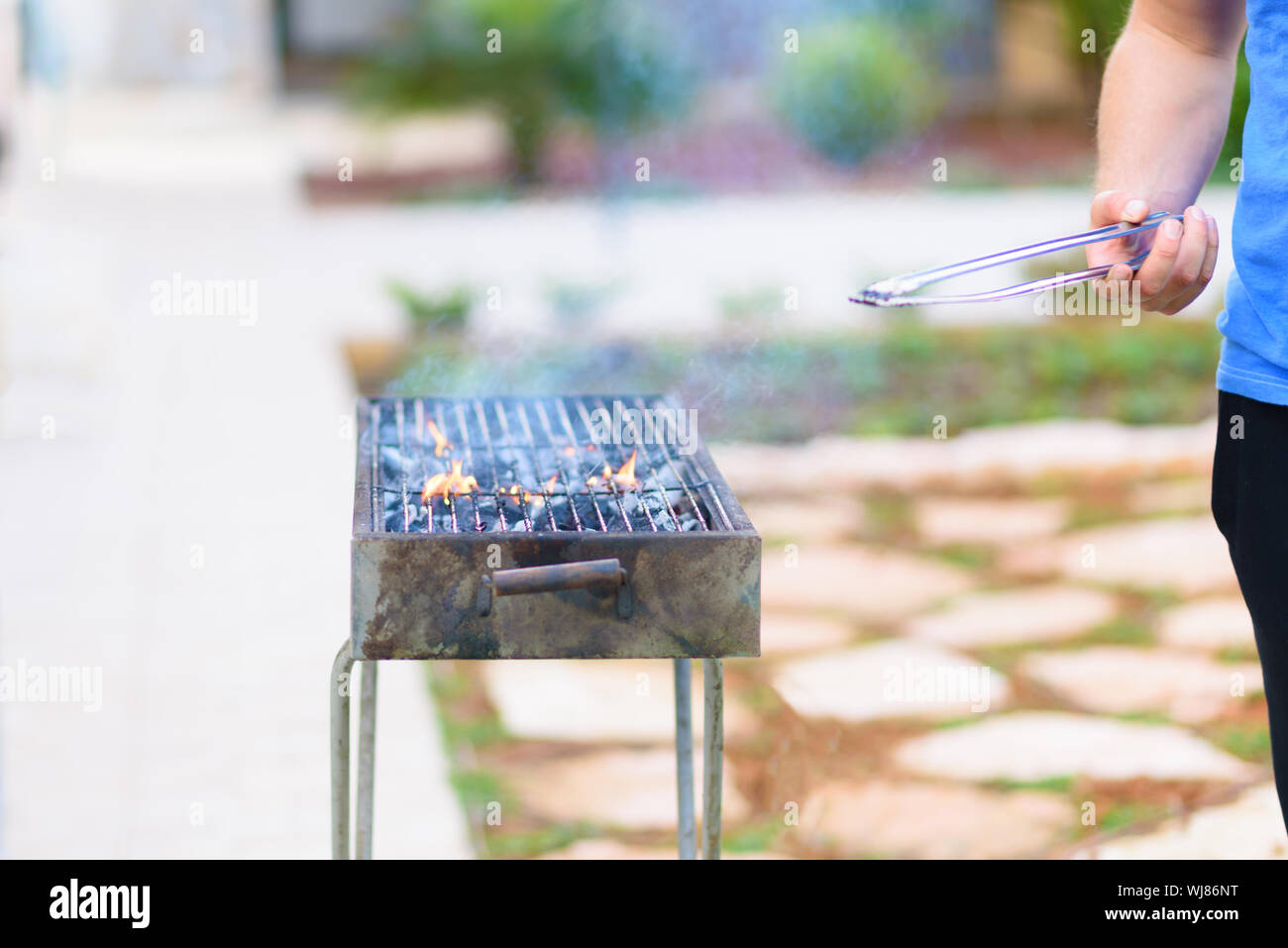 Handsome athlete male prepares barbecue outdoors. Brutal bearded man ...
