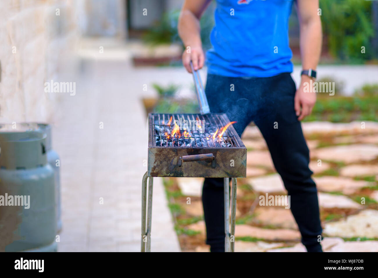 Handsome athlete male prepares barbecue outdoors. Brutal bearded man ...