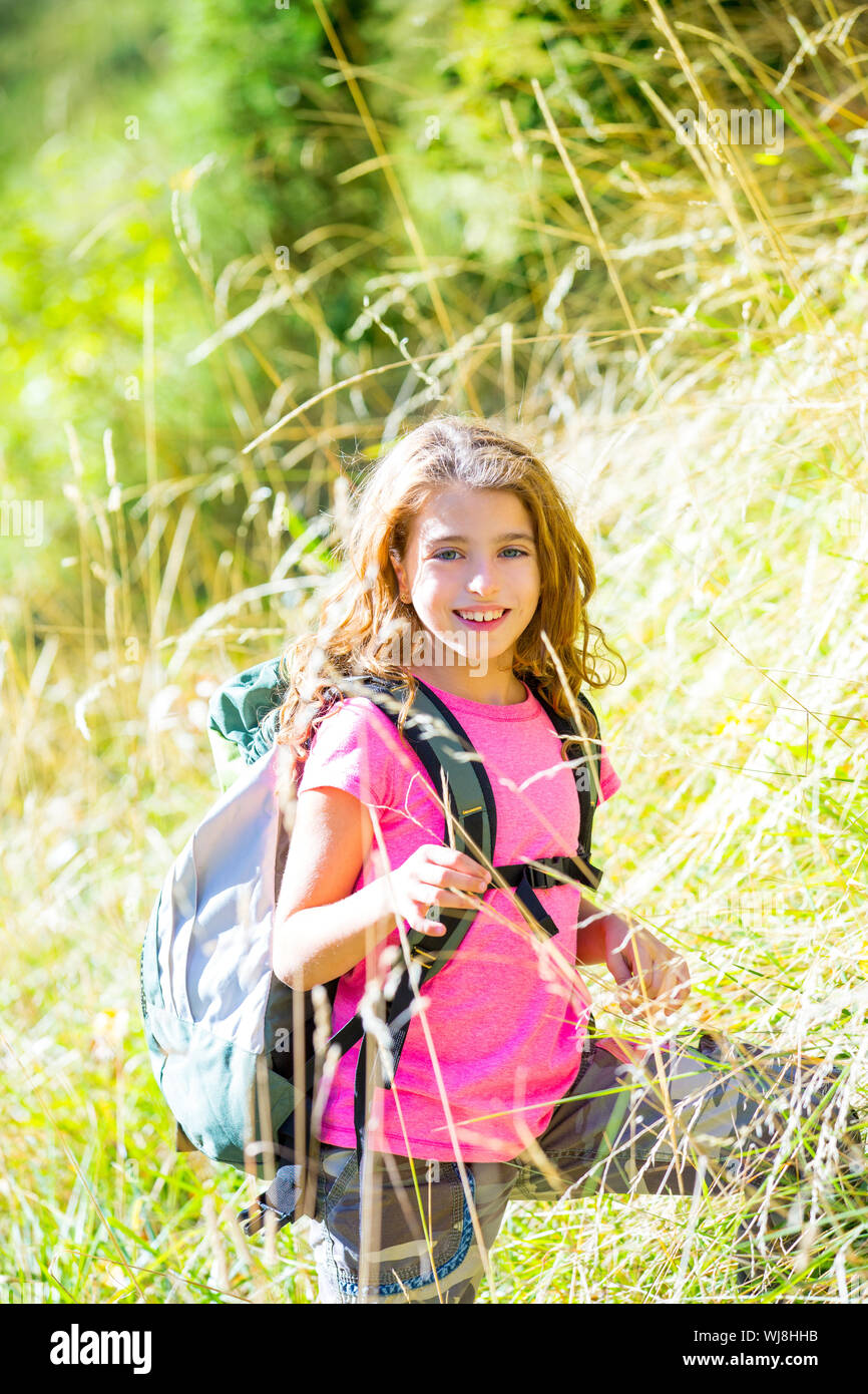 Explorer kid girl walking with backpack between forest grass Stock ...