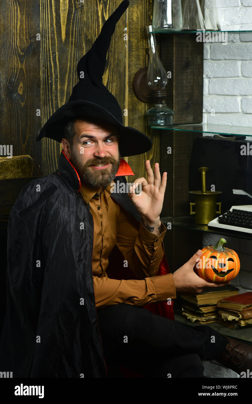 Halloween wizard smiling with pumpkin on wooden wall Stock Photo - Alamy