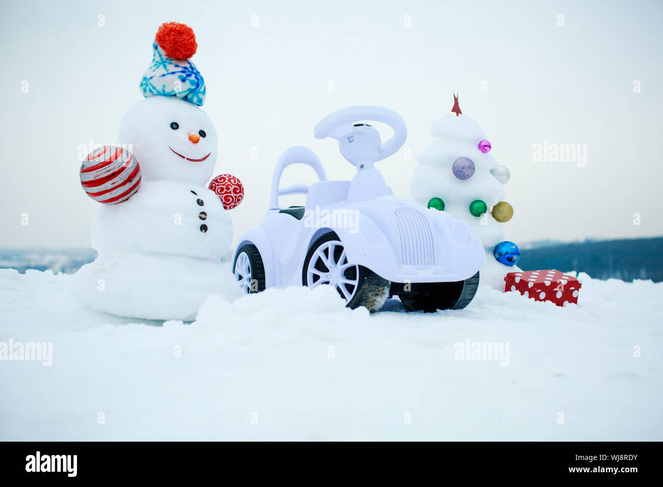 Snowman and toy car on snowy background Stock Photo - Alamy