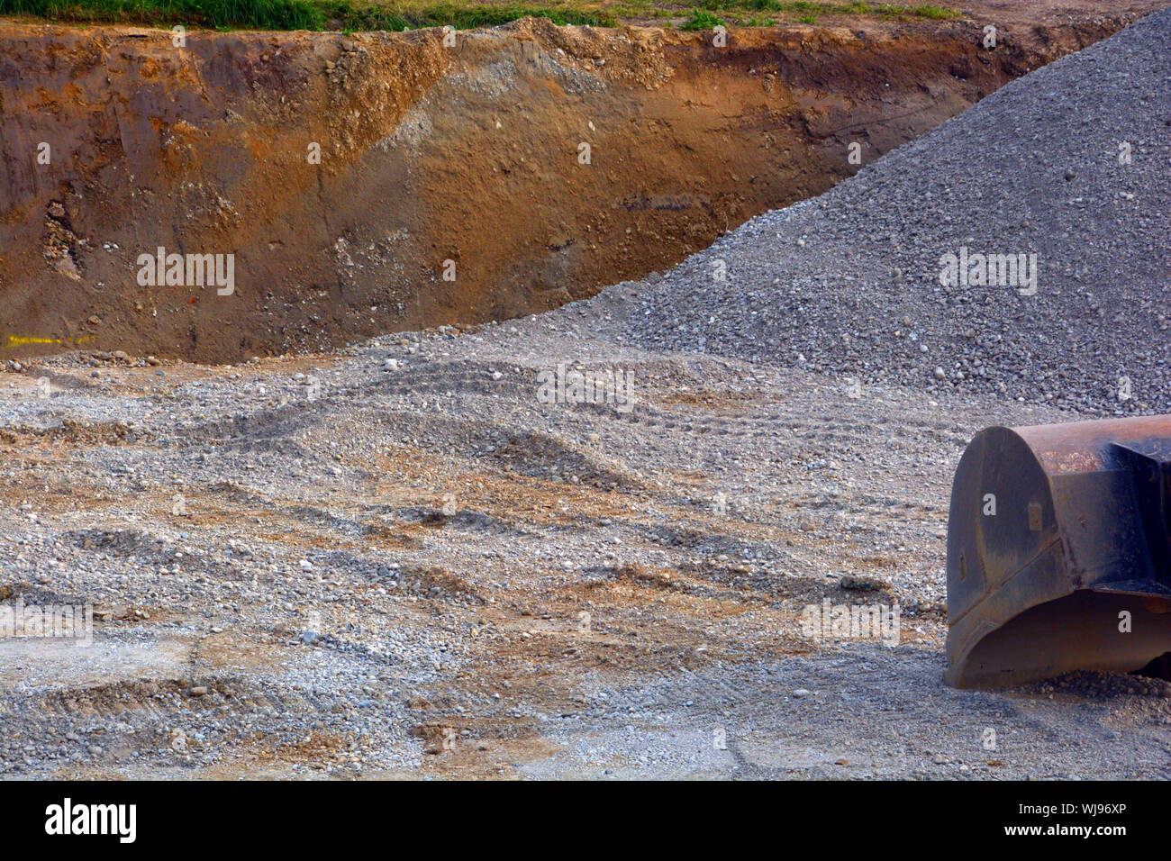 an excavator working removing gravel and sand on a construction site ...