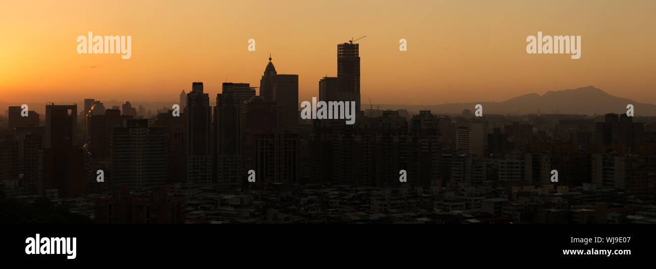 Sunset cityscape with dramatic clouds in orange and yellow color in ...