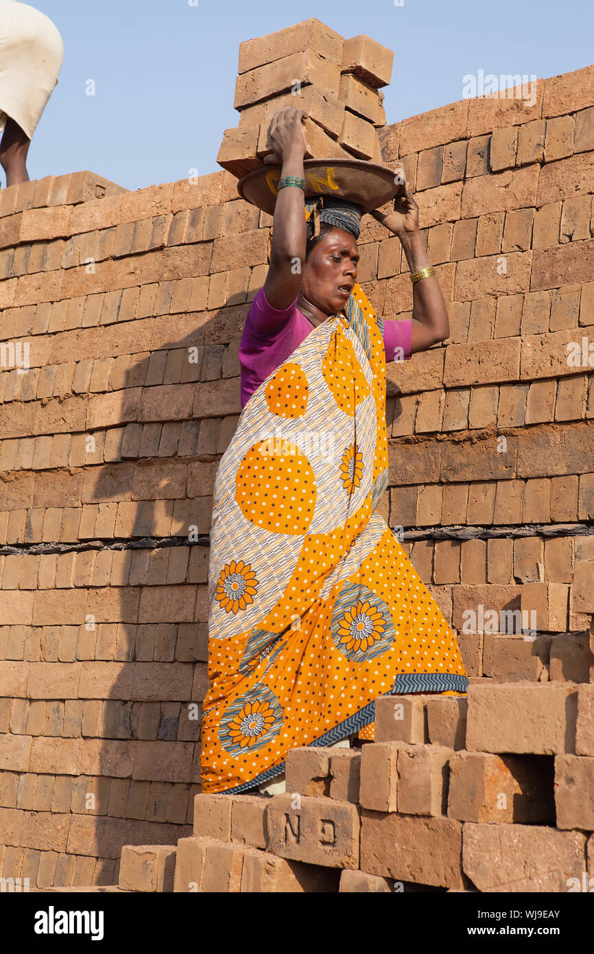 India, Karnataka, Harihar, Female labourer carrying bricks on her head ...
