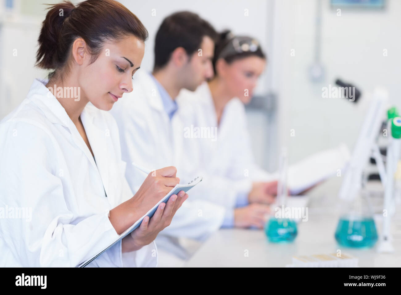 Side view of busy group of researchers working on experiments in the ...