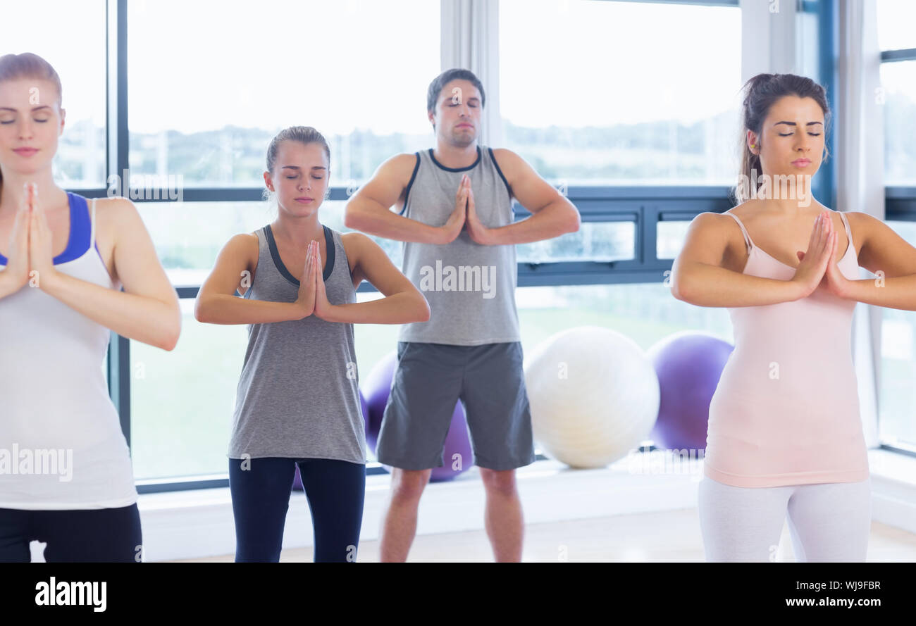 Fitness class and instructor standing in Namaste position at exercise ...