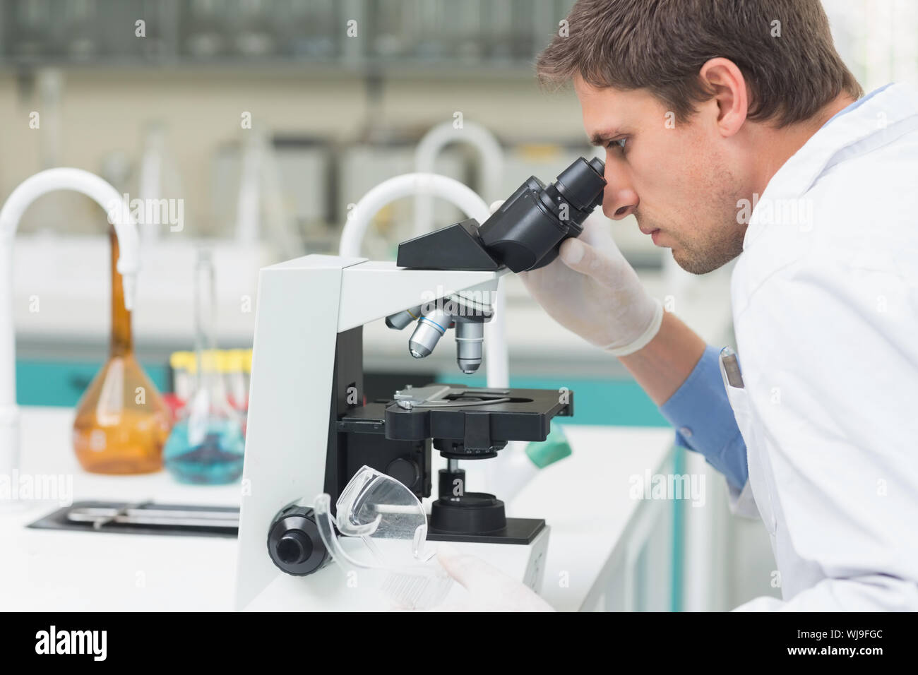 Side view of a male scientific researcher using microscope in the ...