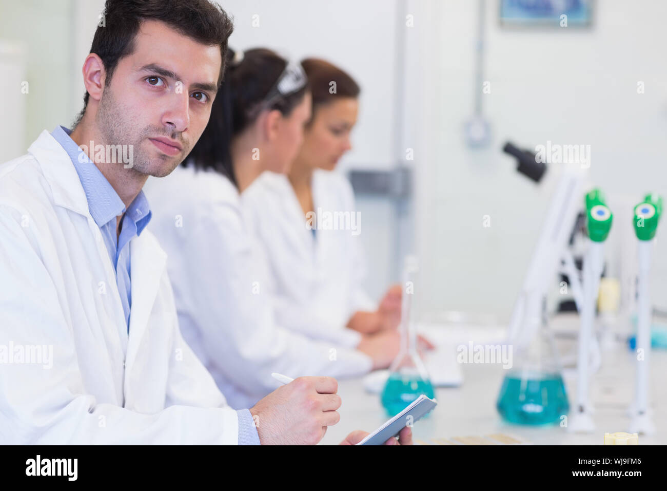 Portrait of a male with researchers working on experiments in the ...