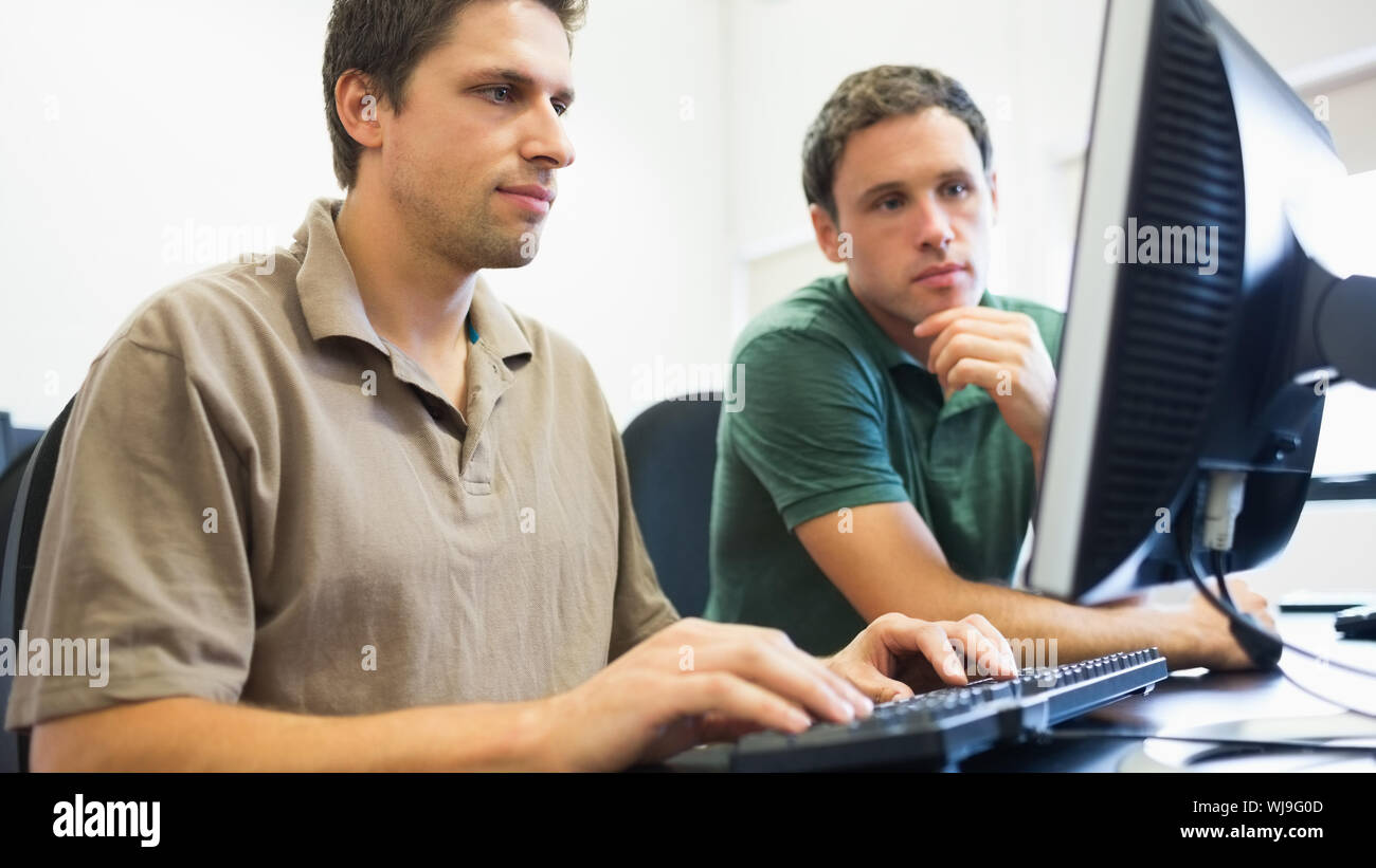 Concentrated teacher and mature student using computer in the computer ...