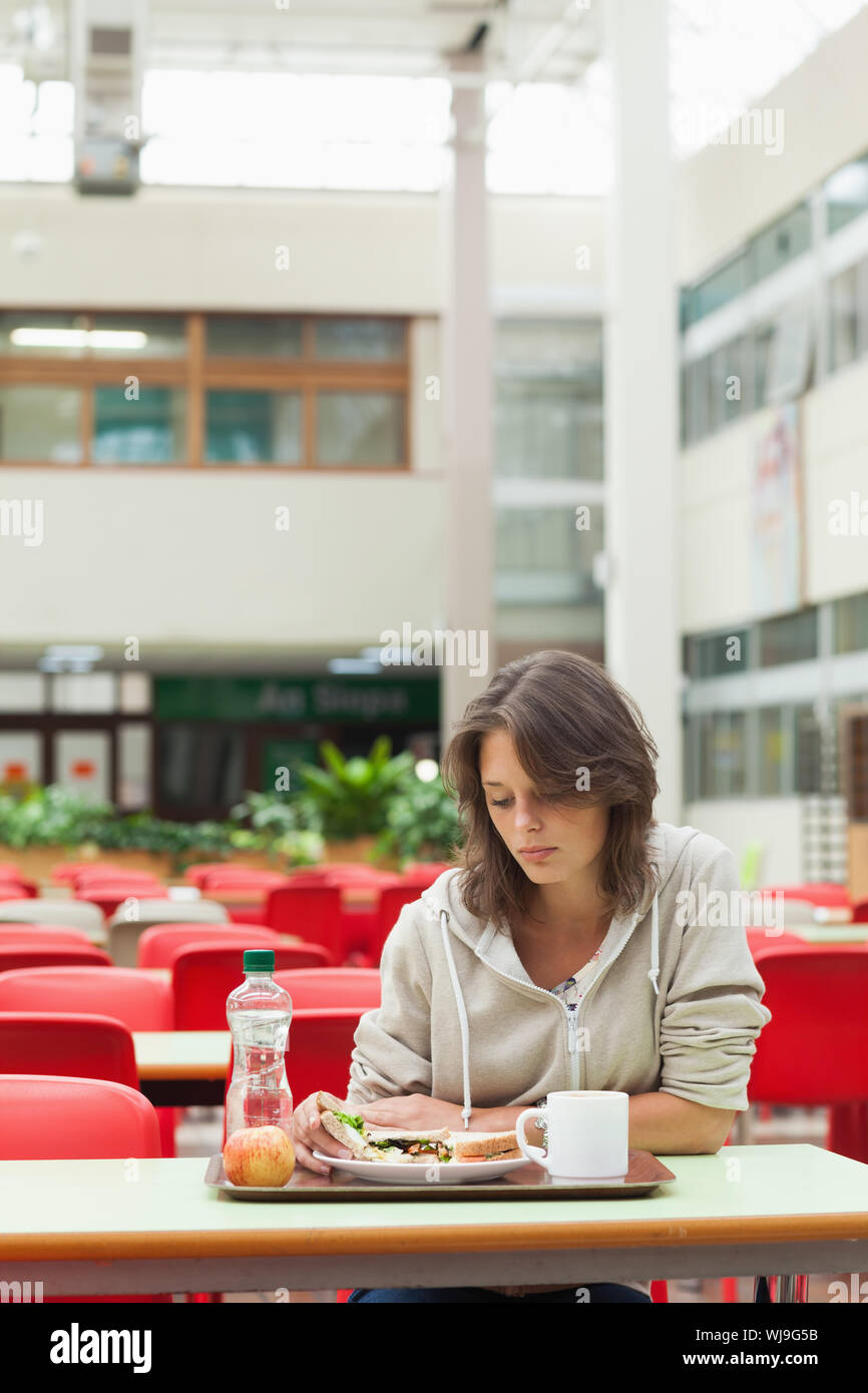 Alone and sad female student sitting in the cafeteria with food tray ...