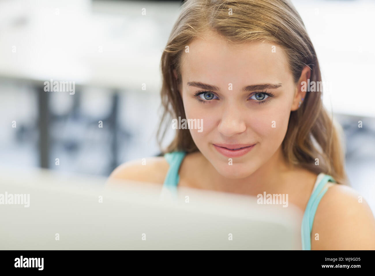 Happy pretty student working on computer in computer room at college ...