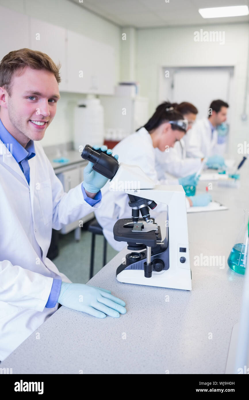 Portrait of a smiling male with researchers working on experiments in ...