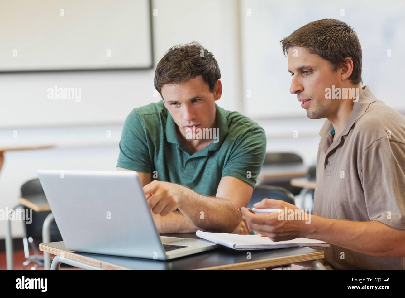 Two concentrated handsome mature students sitting in class while ...