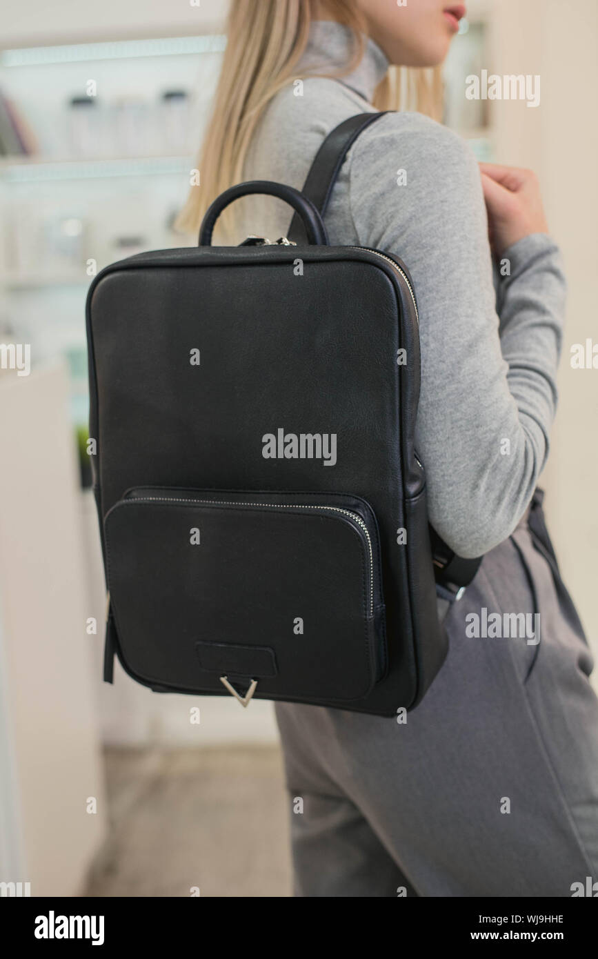 A girl in a gray turtleneck with a leather backpack on her back ...