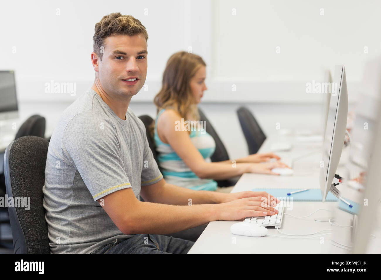 Two happy students working on computer individually in computer room ...