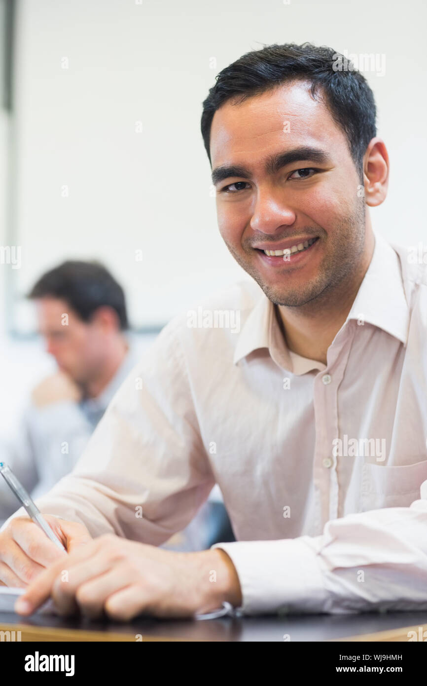 Portrait of a mature student taking notes with others in lecture in ...