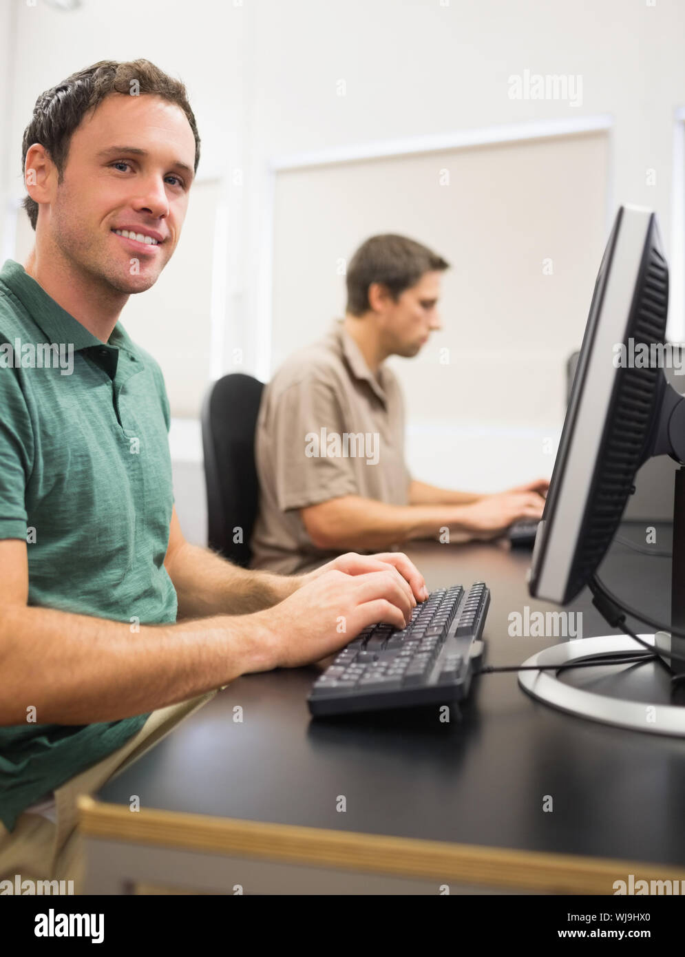 Portrait of a smiling man by other mature student using computers in ...