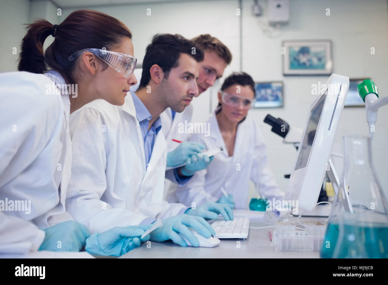 Side view of serious researchers looking at computer screen in the ...