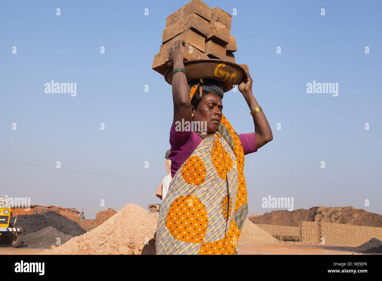 India, Karnataka, Harihar, Labourer carrying bricks on her heads at a ...