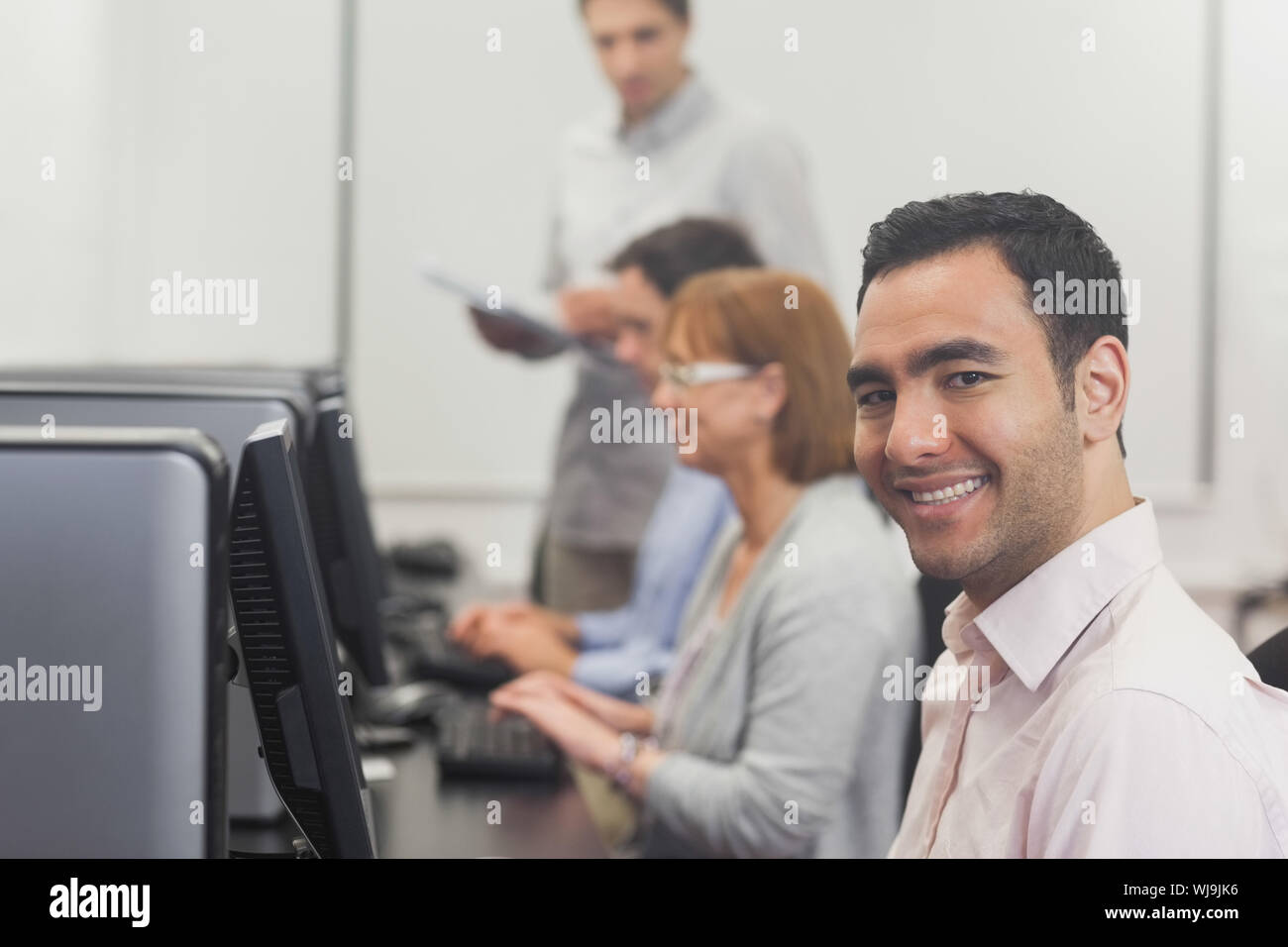 Concentrated female mature student sitting in computer class working on ...