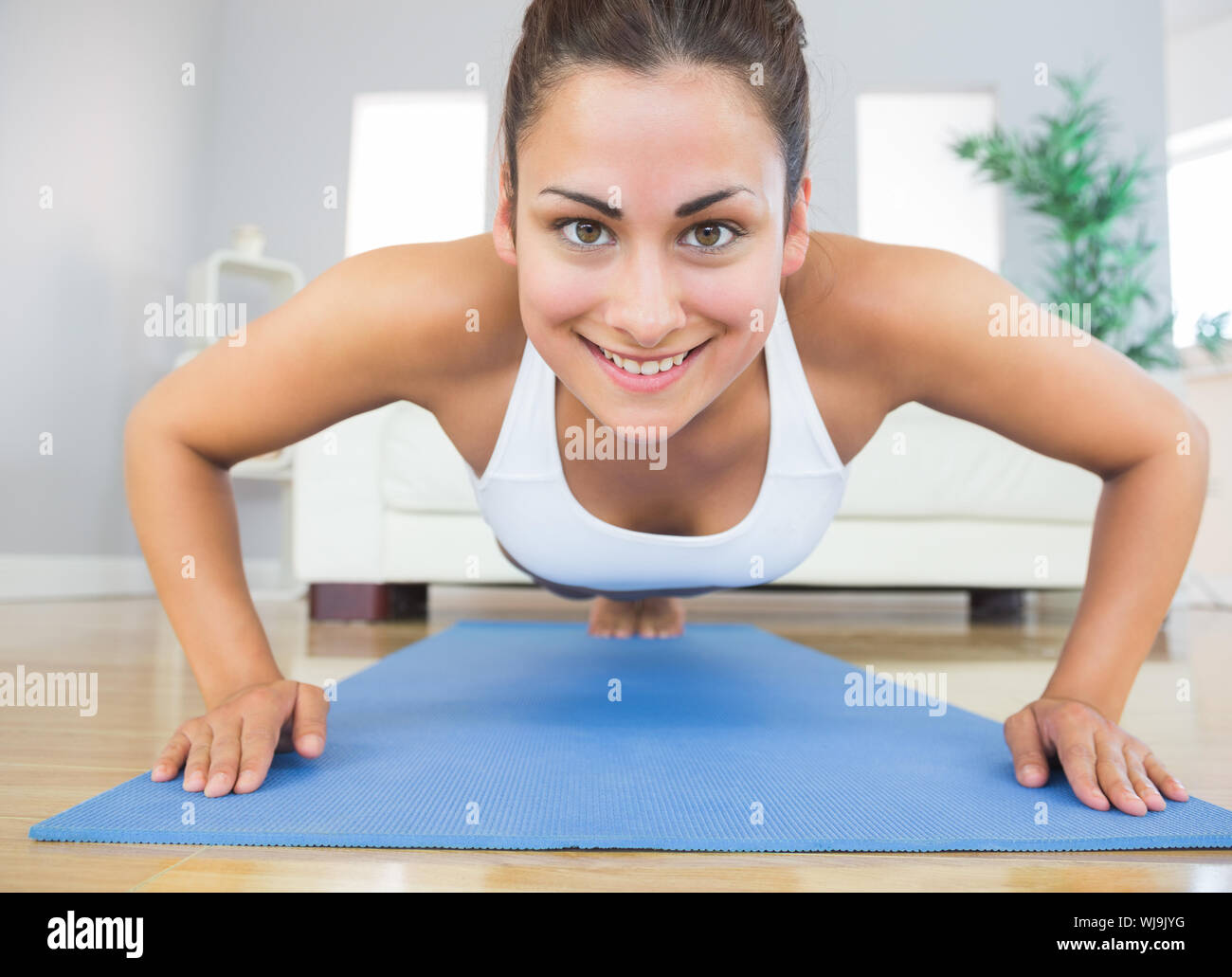 Fit young woman practicing press ups on a blue exercise mat in her ...