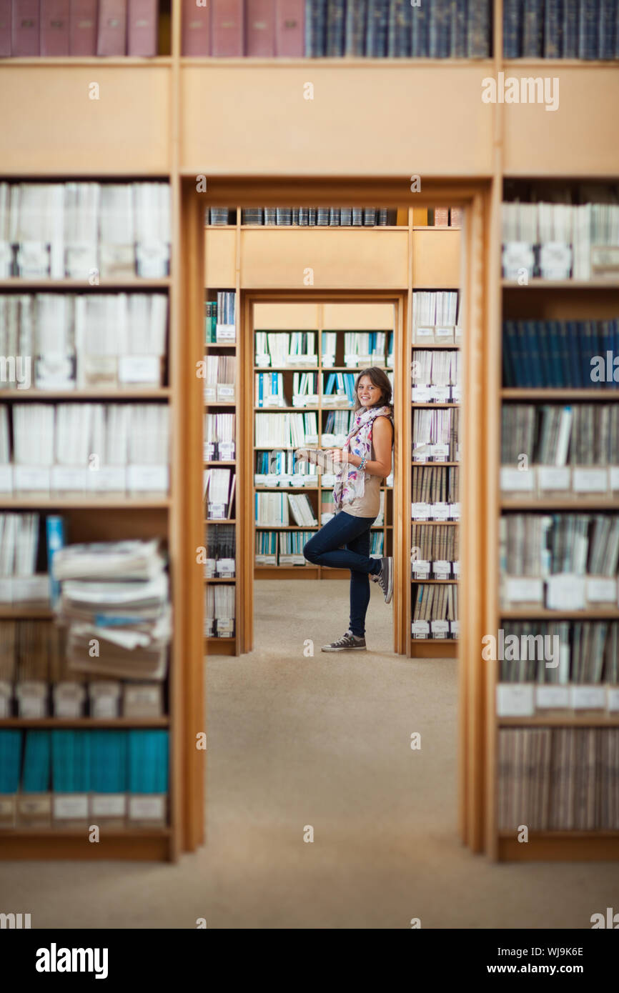 Full length side view of a smiling female student standing in the ...