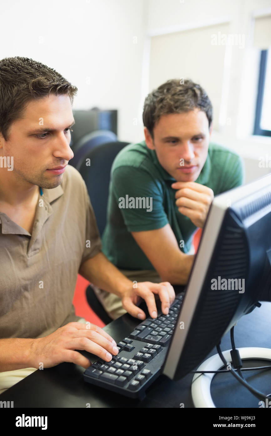 Concentrated teacher and mature student looking at computer screen in ...