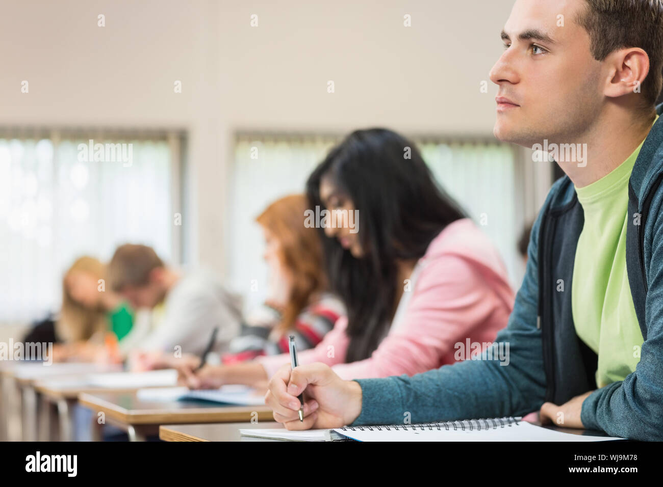 Side view of a group of young students writing notes in the classroom ...