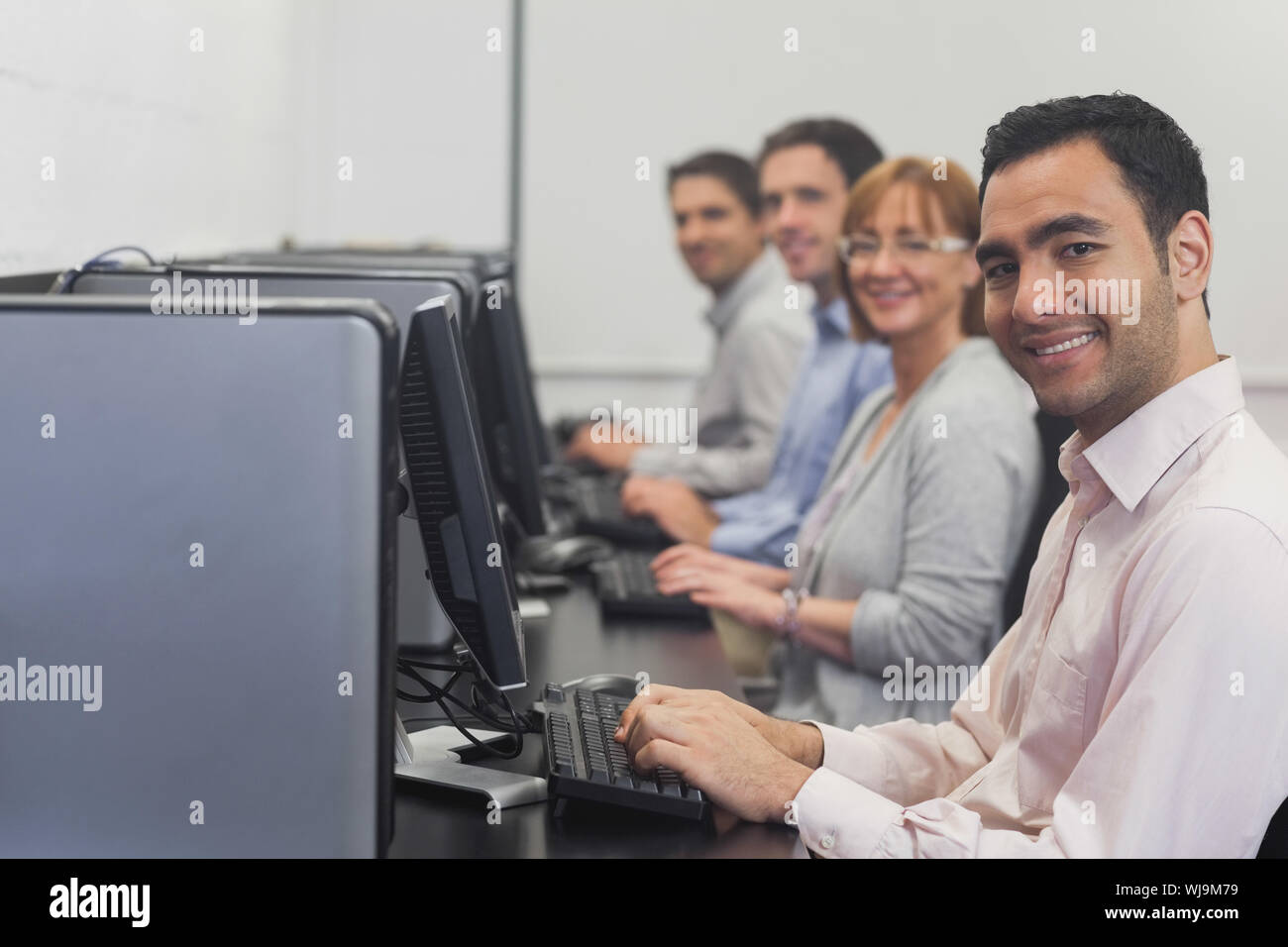 Computer class sitting in front of computers smiling at camera Stock ...